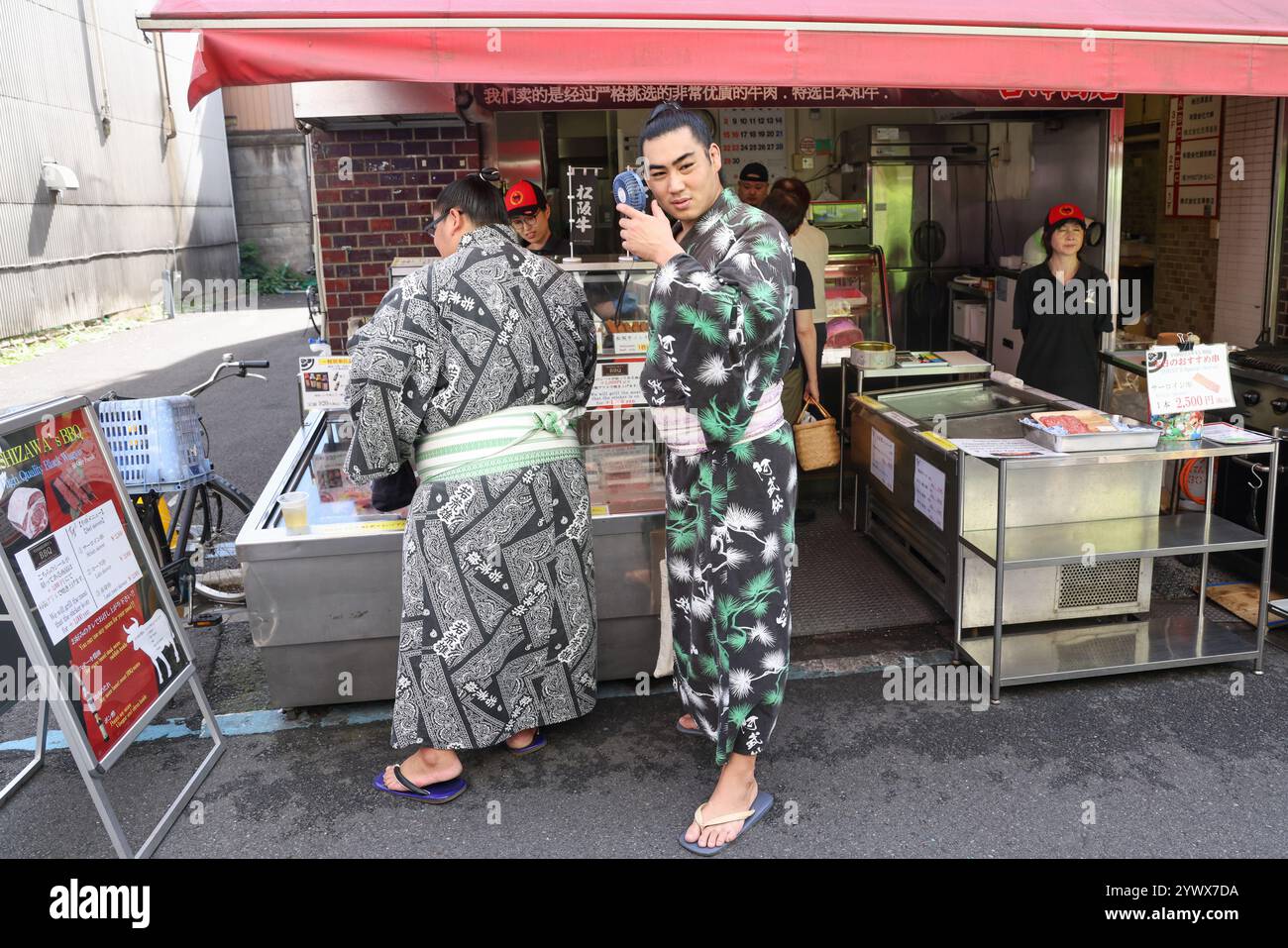 Two Sumo wrestlers at a street food stall in the Tsukiji Outer Market ...