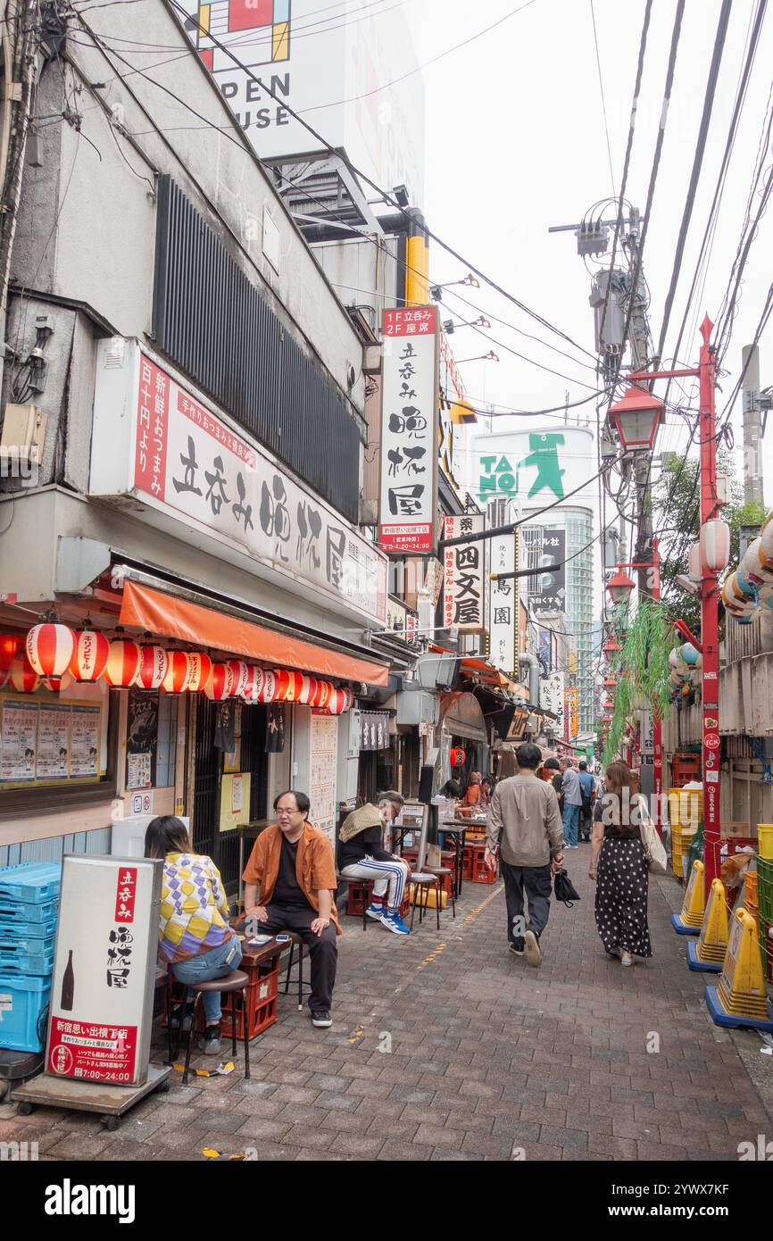People eating at a street food stall in Memory Lane alley in Omoide ...