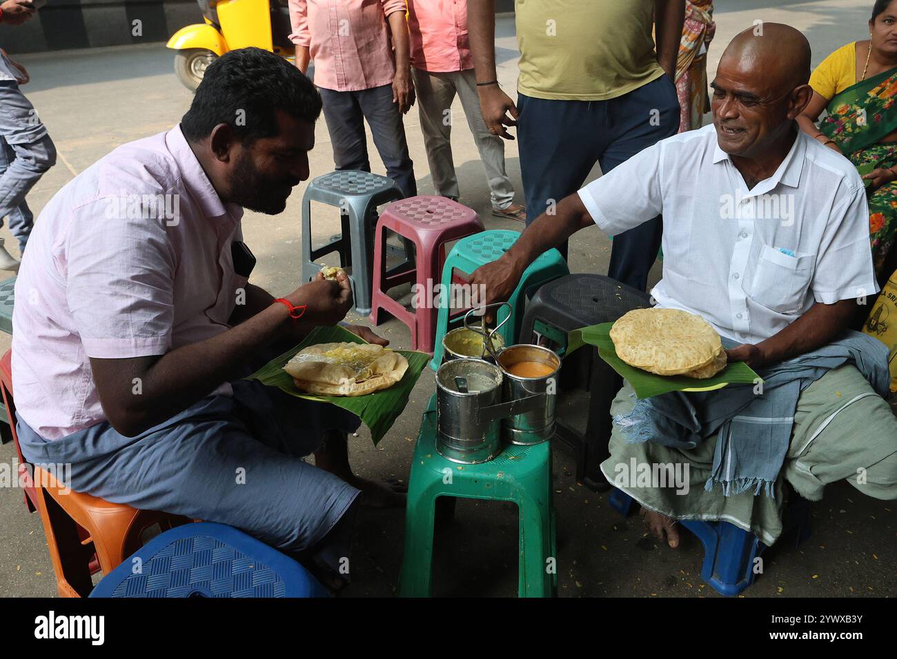 Men eating puri using a banana leaf as a plate at a street food stall ...