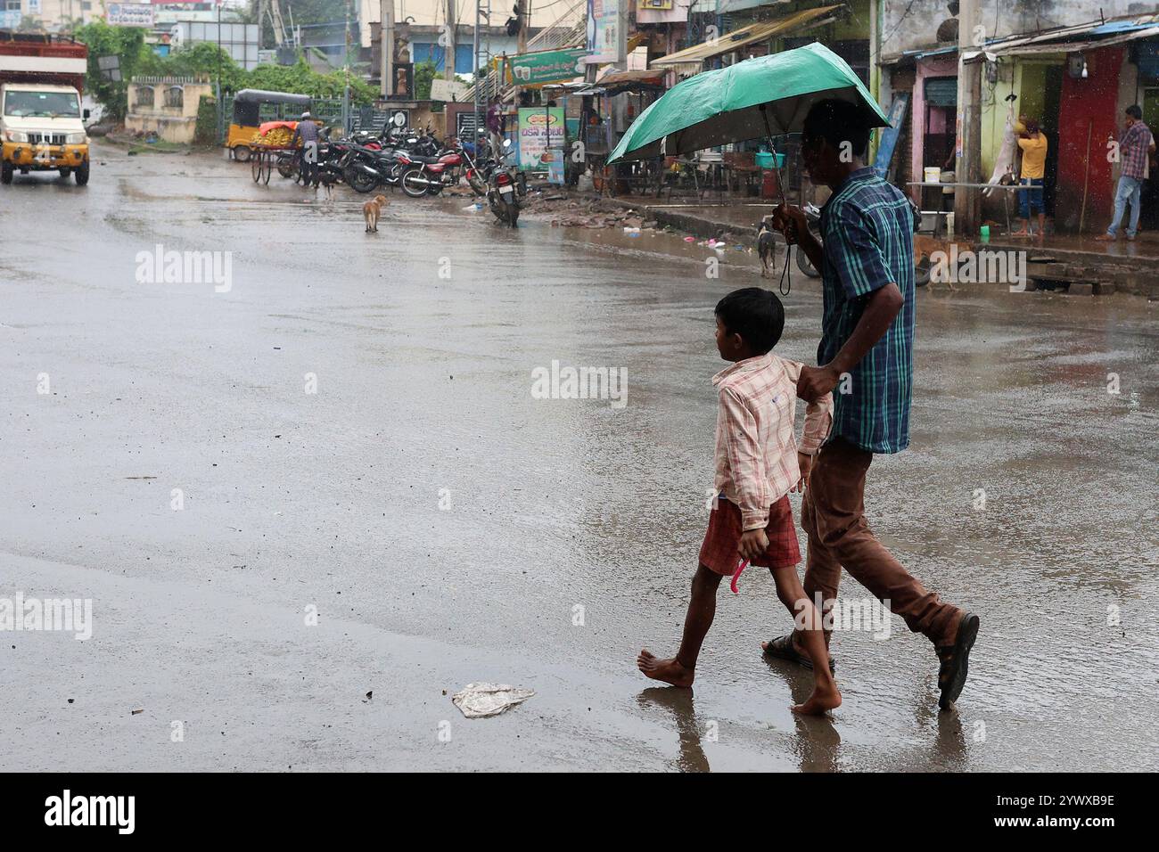 A father and son walk through the wet streets of Nandyal during the ...