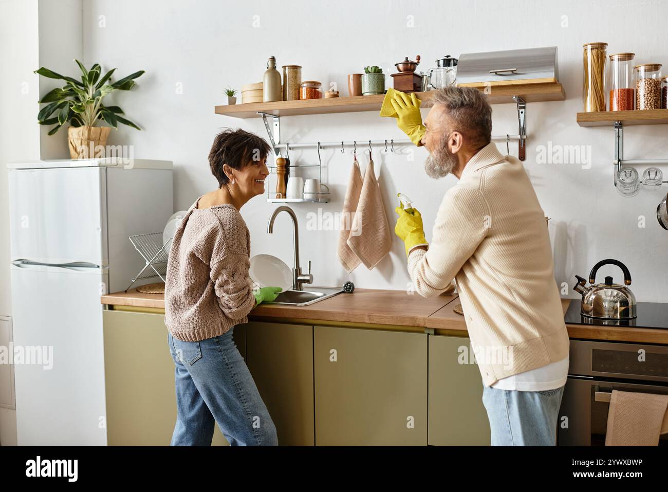 A happy couple engages in a playful moment while washing dishes in ...