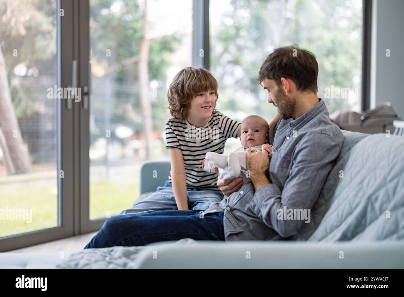 Father and older son taking care of little baby at home Stock Photo - Alamy