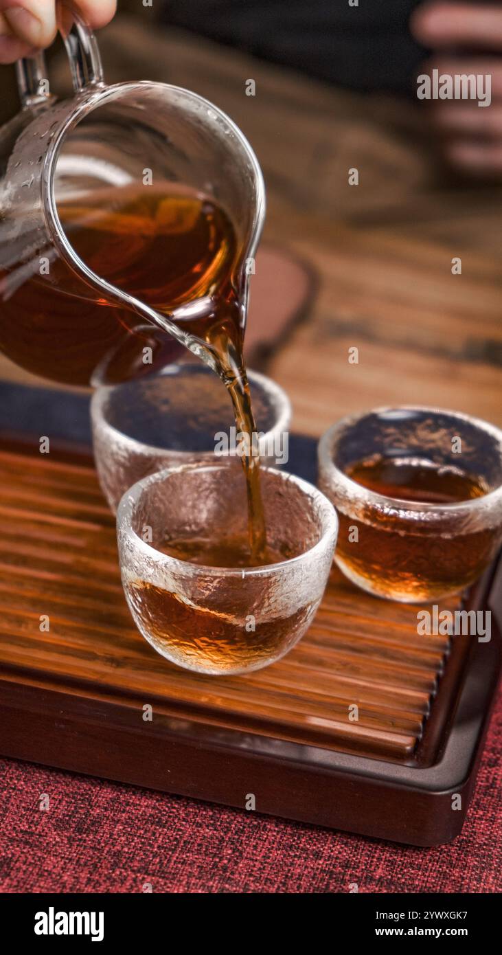 Pouring tea gently into delicate glass cups creates a serene and ...