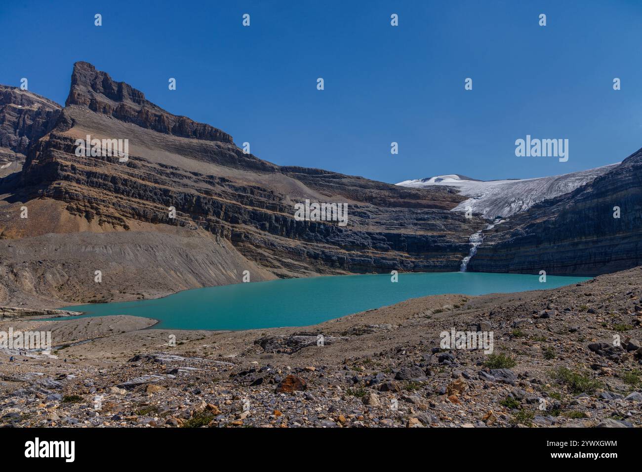 A stunning turquoise lake at the base of steep mountain cliffs, with a ...