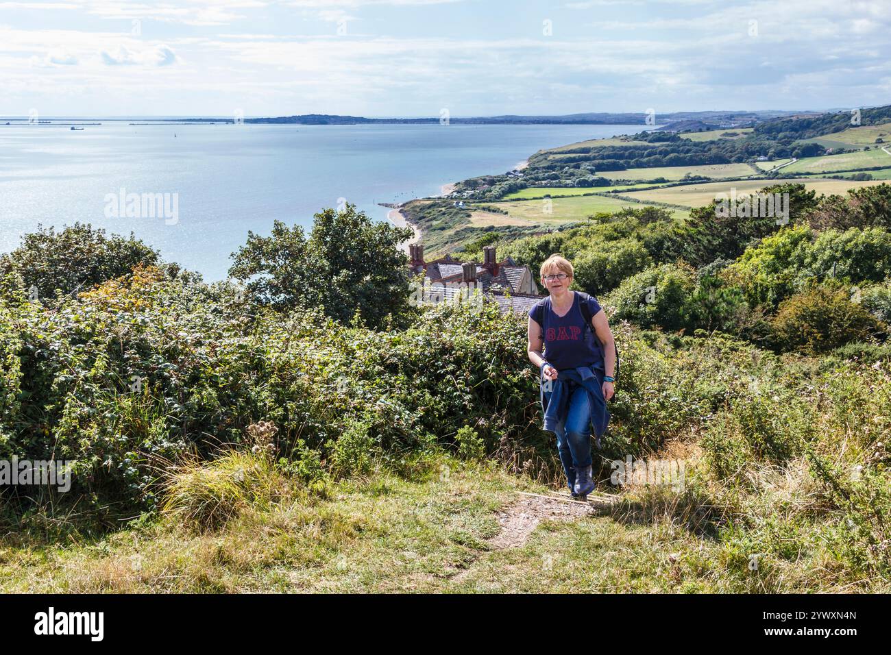 A female walker climbing steps on the South West Coast Path overlooking ...