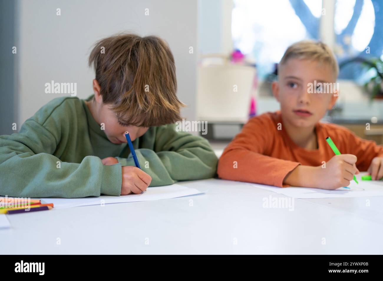 Two focused boys are concentrating on their drawings, using colored ...