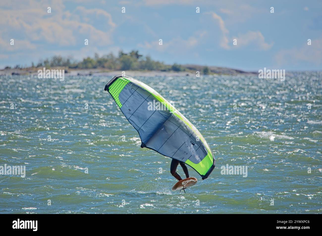 Man is wing foiling using handheld inflatable wing and hydrofoil ...