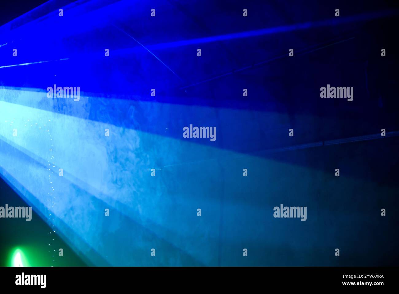 A blue and green light show with a blue wall. The blue light is on the ...