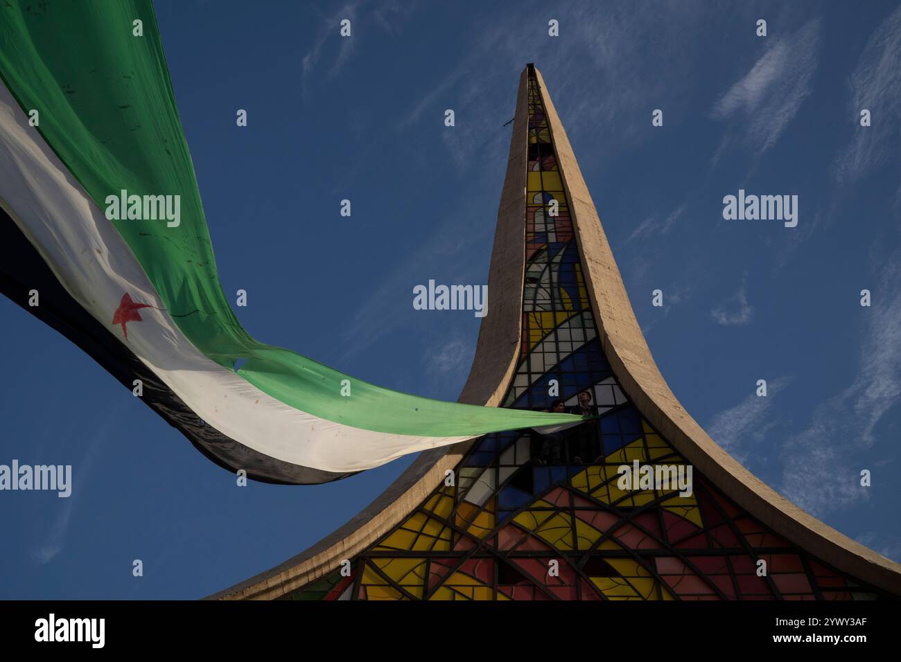 People hold a giant Syrian opposition flag at the Damascene Sword ...