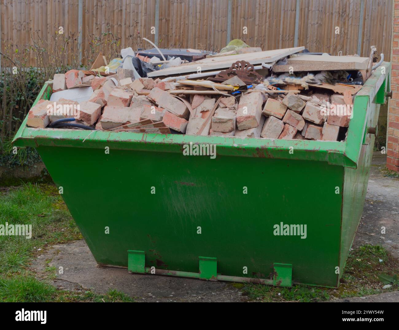 A dumpster or skip, full to overflowing with bricks and other building ...