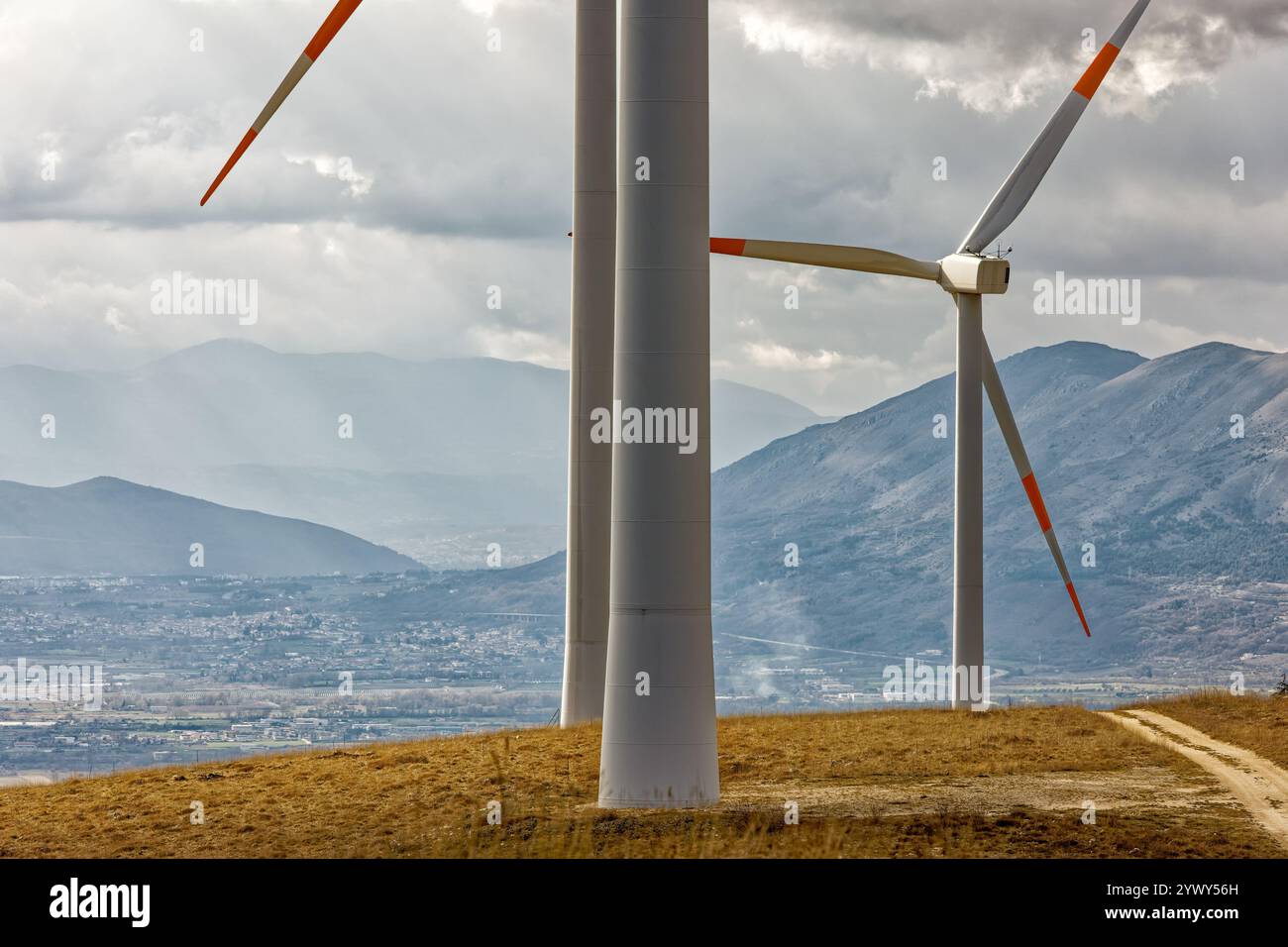 Wind turbines on a hilltop during sunset with dramatic clouds and sun ...
