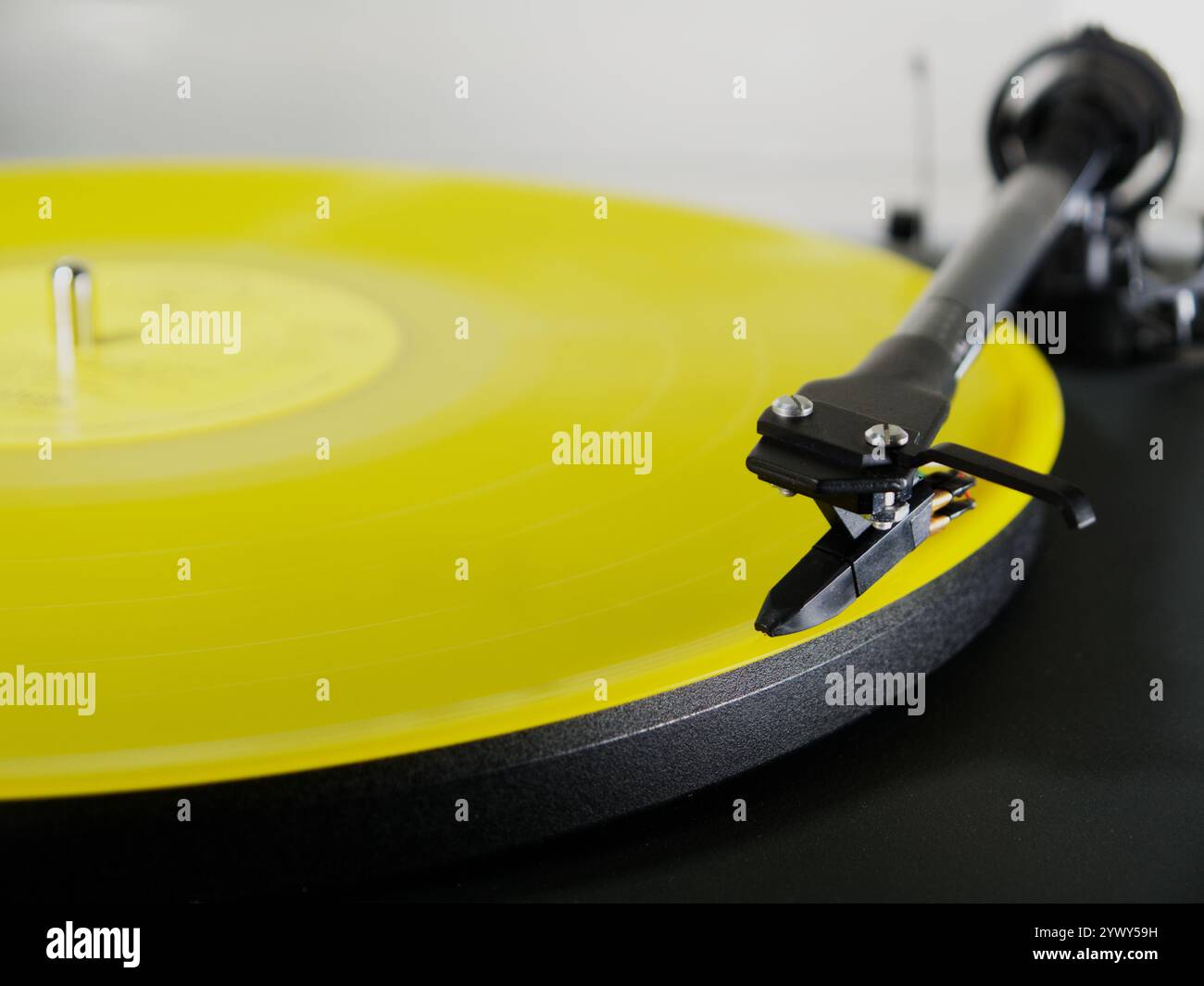 Closeup of a yellow vinyl LP record on a turntable, with the tonearm ...