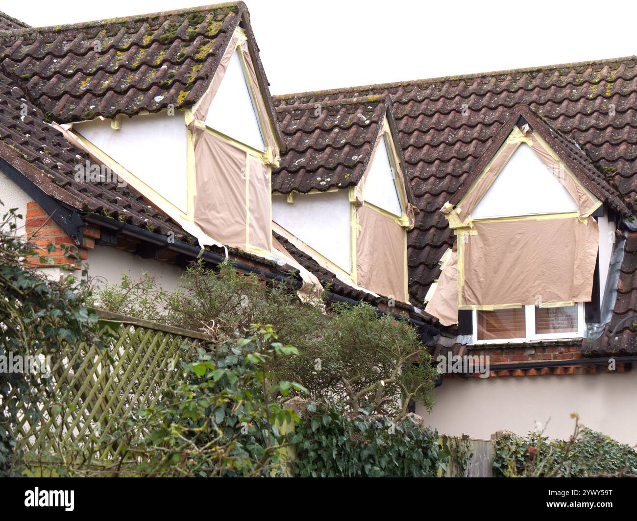 A house roof with three dormer windows, masked with protective paper ...