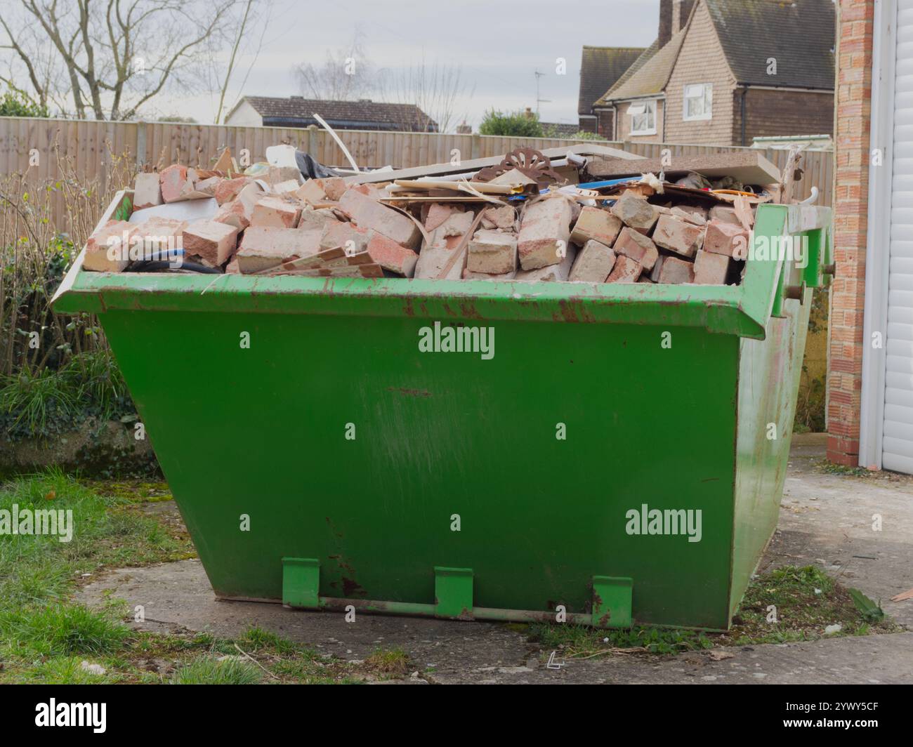 A dumpster or skip, full to overflowing with bricks and other building ...
