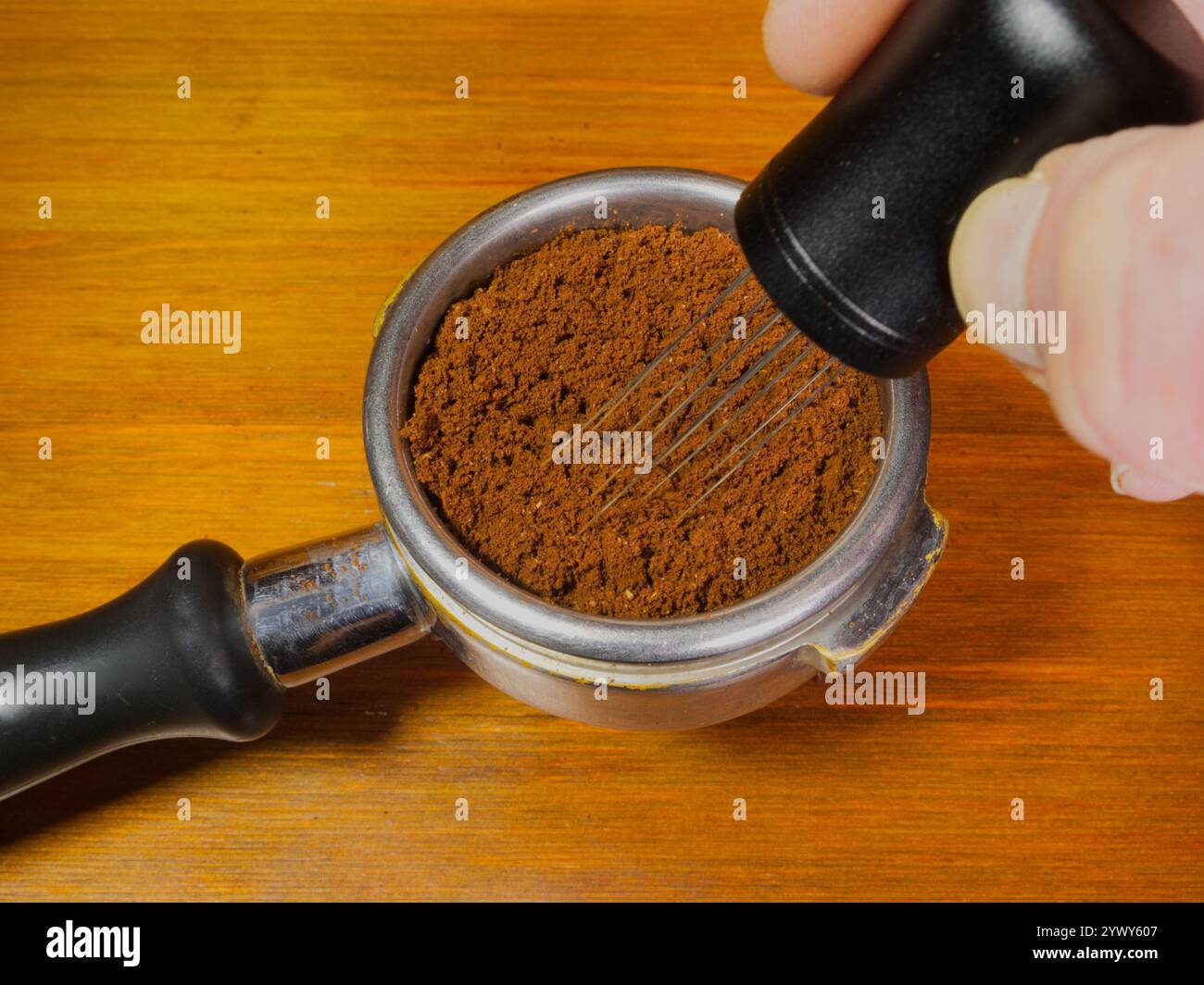 Fingers gripping a barista’s needle distribution tool in a portafilter ...