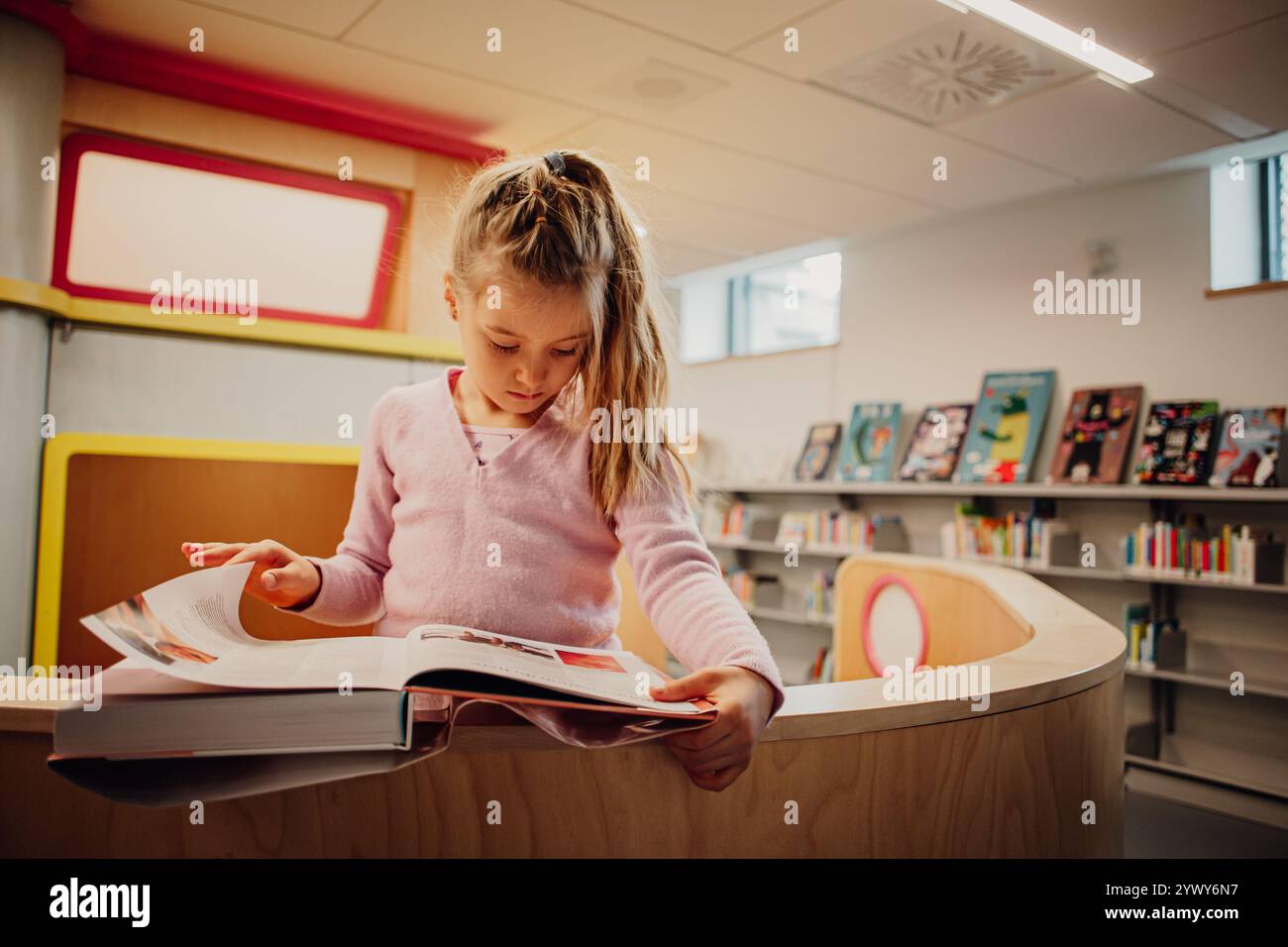 Little girl reading in library's creative space Stock Photo - Alamy