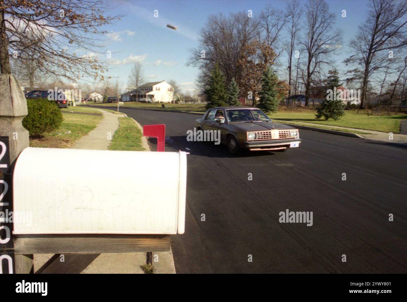 PA, USA, approx. 1985. Man delivering newspapers into a neighborhood ...