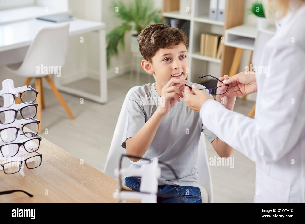 Optician doctor giving a new pair of eyeglasses to child patient in ...