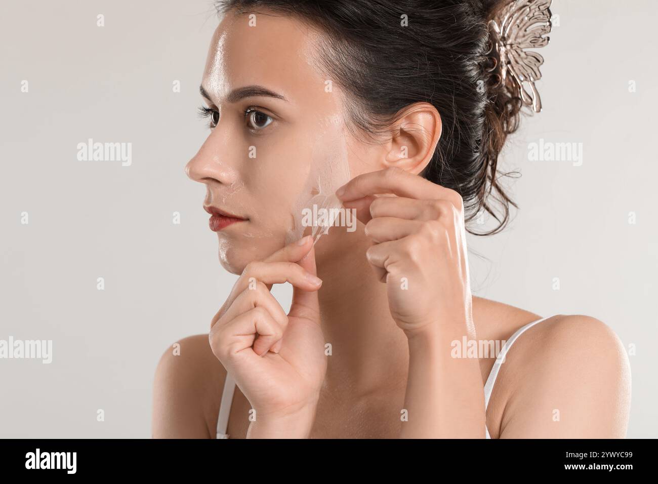 Beautiful woman peeling off face mask on light grey background Stock ...