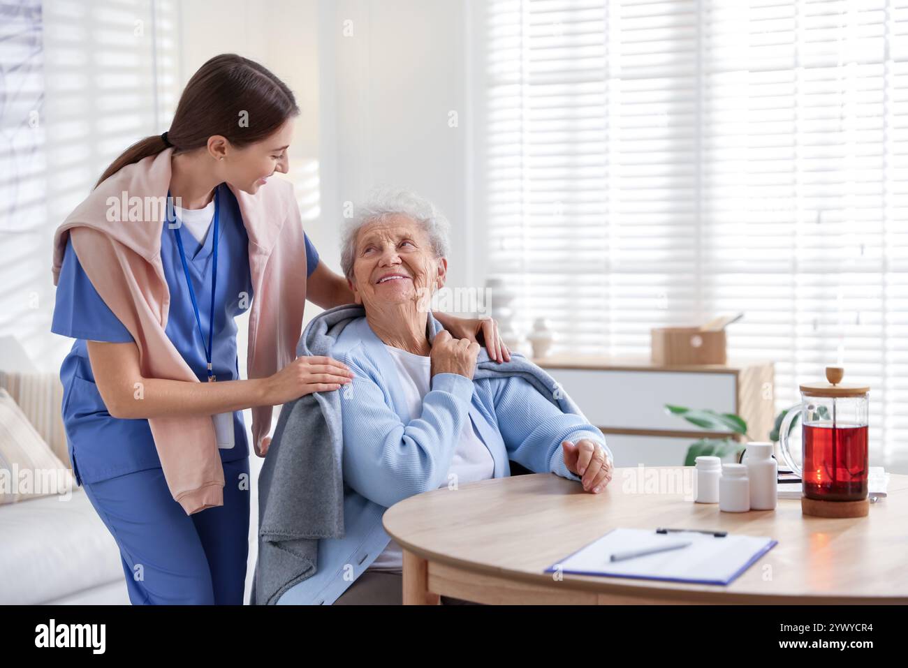 Caregiver covering senior woman with blanket indoors. Home health care service Stock Photo - Alamy