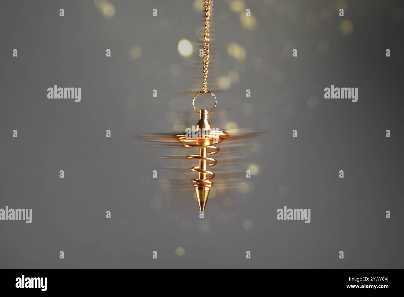 Hypnosis session. Golden pendulum swinging on grey background, motion blur effect. Magic lights ...