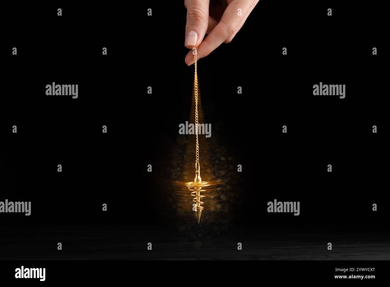 Hypnosis session. Woman swinging golden pendulum on black background ...