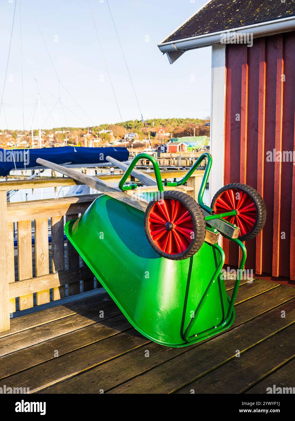 A bright green wheelbarrow is flipped upside down on a wooden dock ...