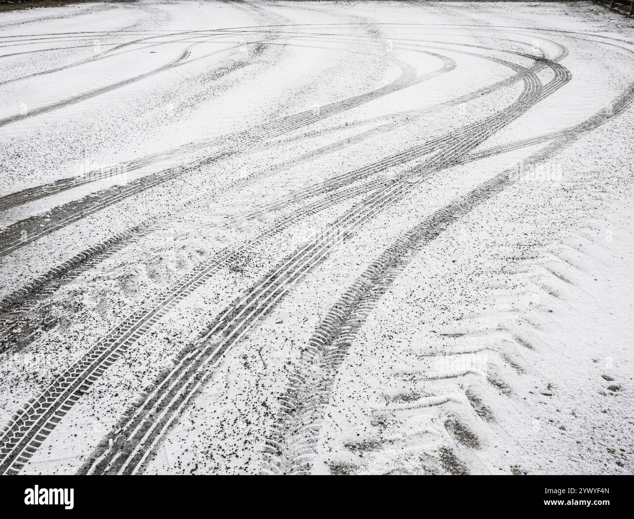 Tire tracks wind across a snowy surface, creating patterns left by cars ...