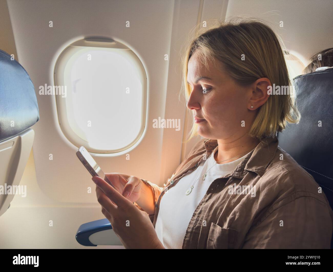 Passenger woman is flying in plane. Girl using phone sitting by ...