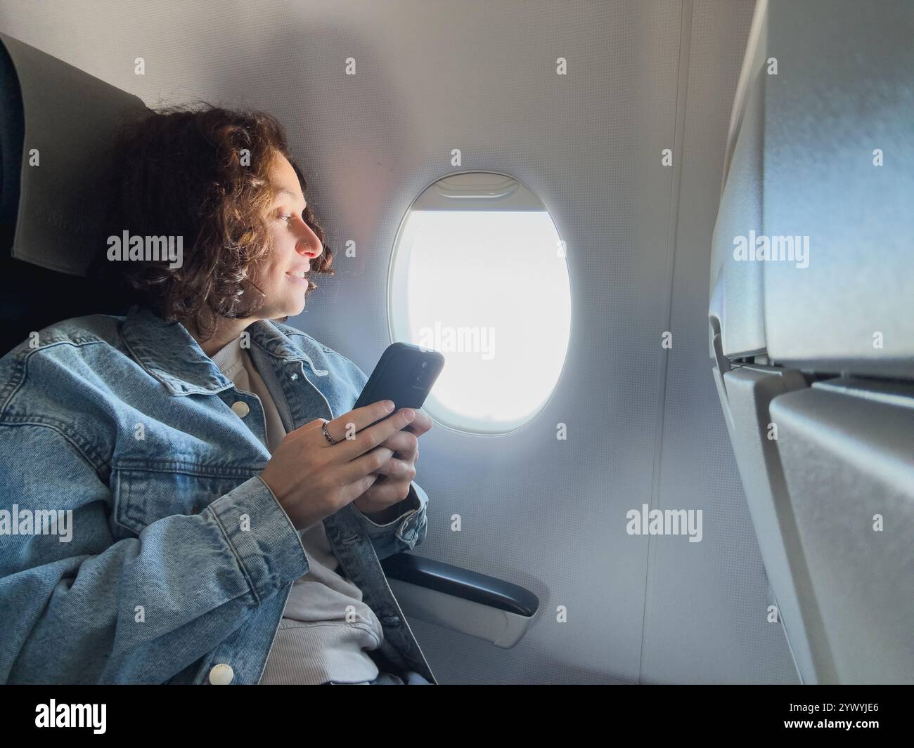 Passenger woman is flying in plane. Girl using phone sitting by ...