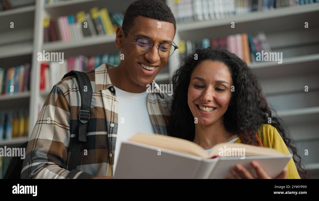 African American man Hispanic Latina woman students smile reading book ...