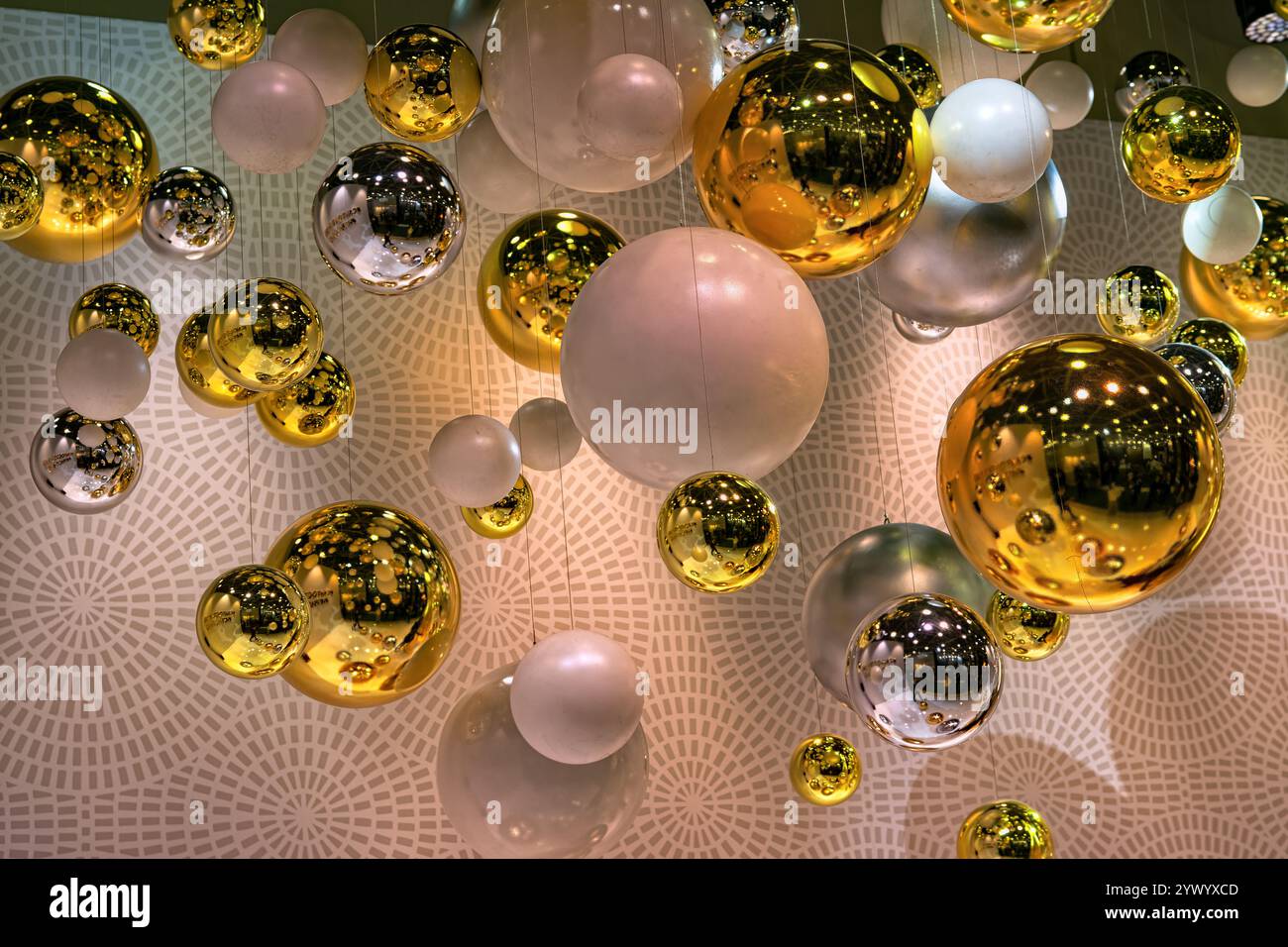 Many different colored balls (gold, silver, white) hang from ceiling ...