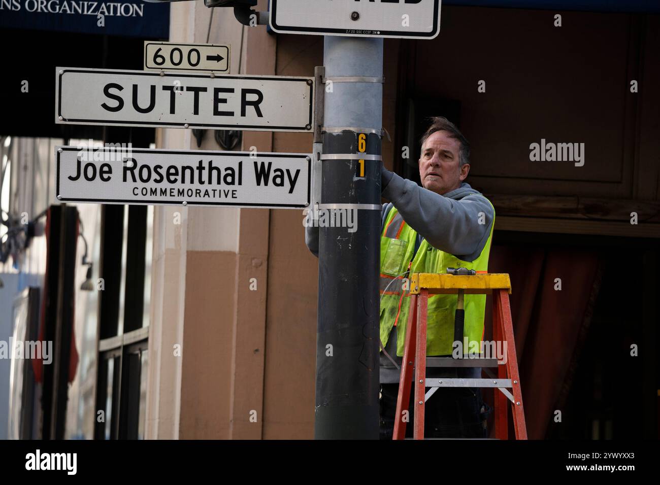 An SFMTA worker installs the Joe Rosenthal Way street sign during the ...