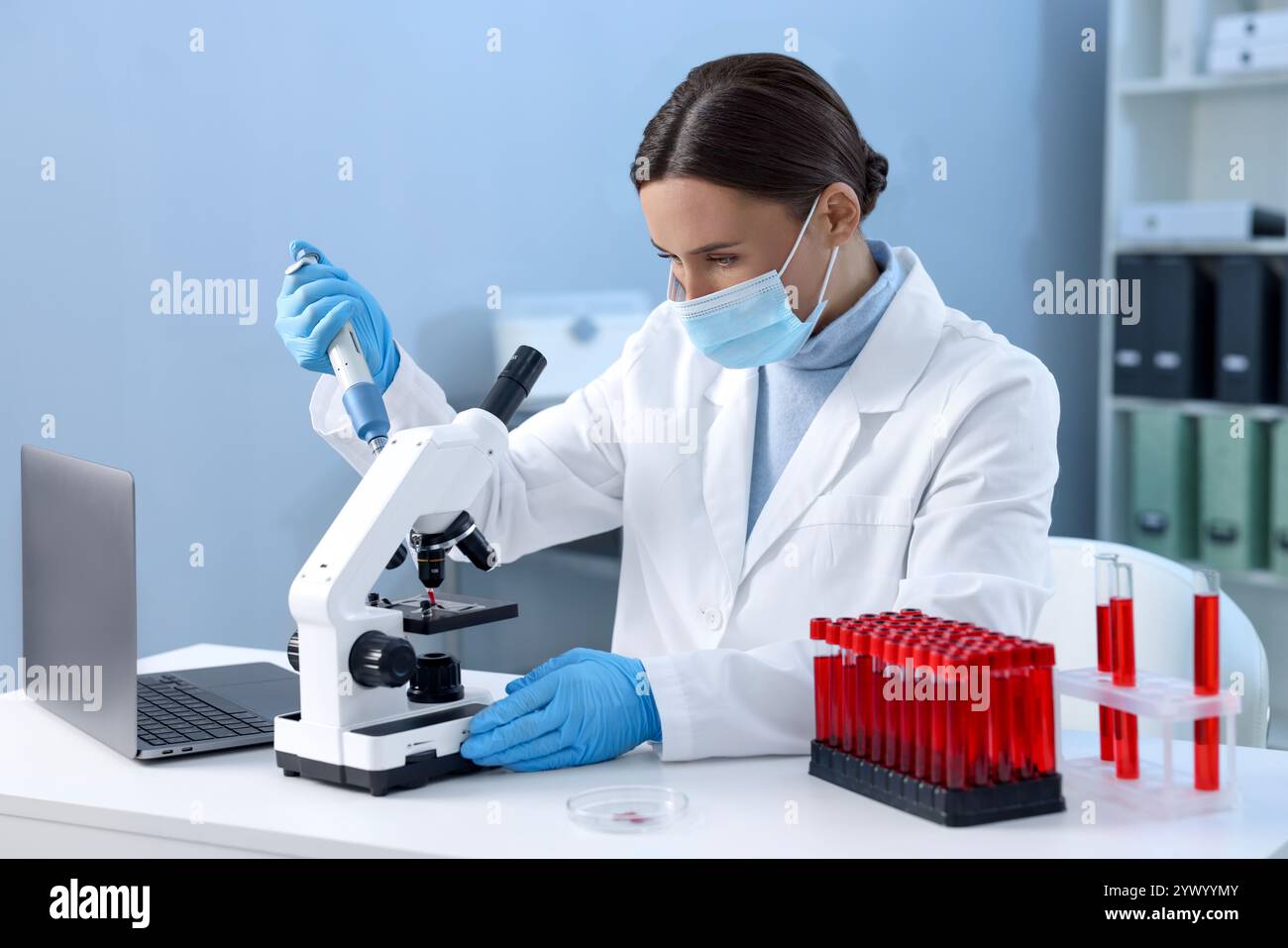 Laboratory testing. Doctor dripping blood sample onto glass slide while ...