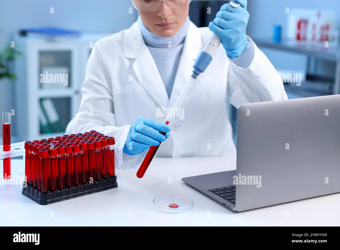 Laboratory testing. Doctor dripping blood sample into test tube at ...