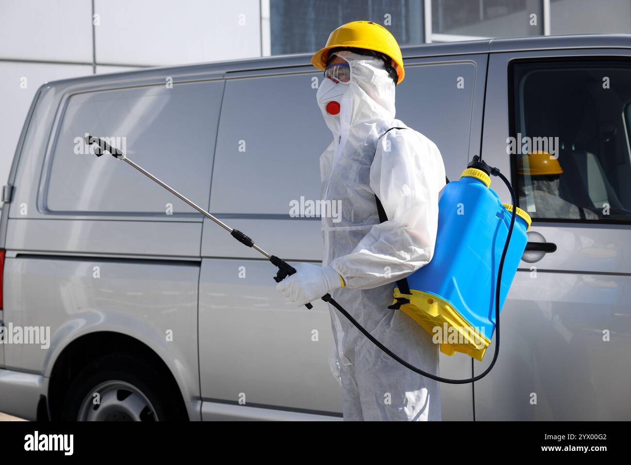 Pest control worker with spray tank near gray minibus outdoors Stock ...
