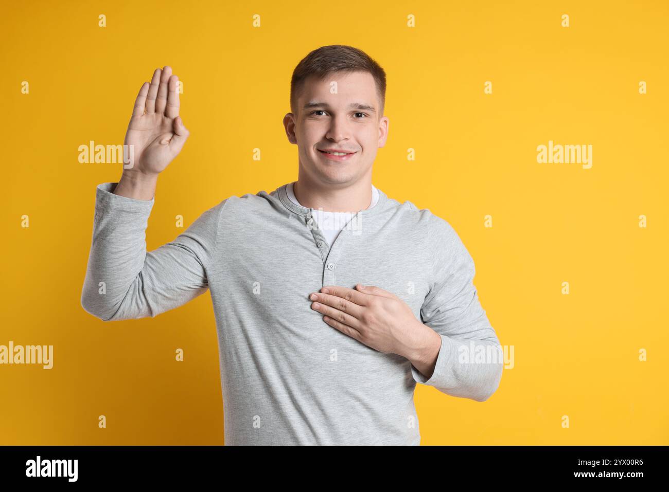 Man making promise with raised hand on orange background. Oath gesture ...