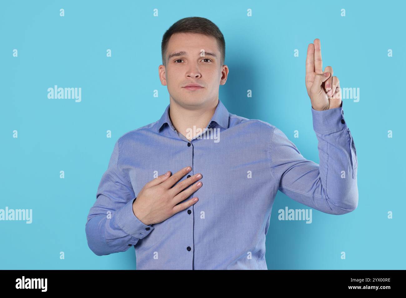 Man showing oath gesture on light blue background. Making promise Stock ...