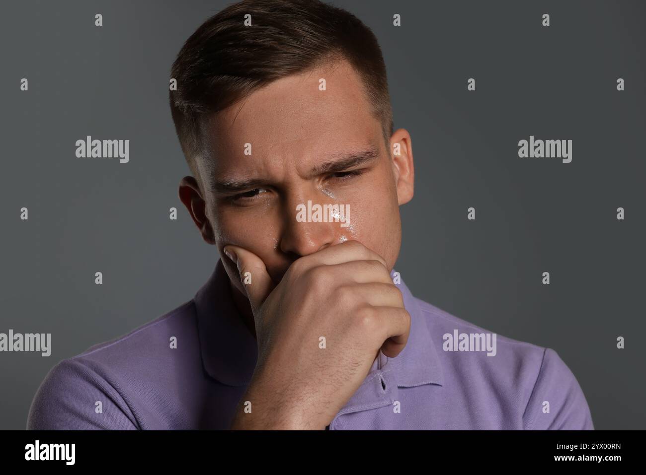 Distressed young man crying on grey background Stock Photo - Alamy