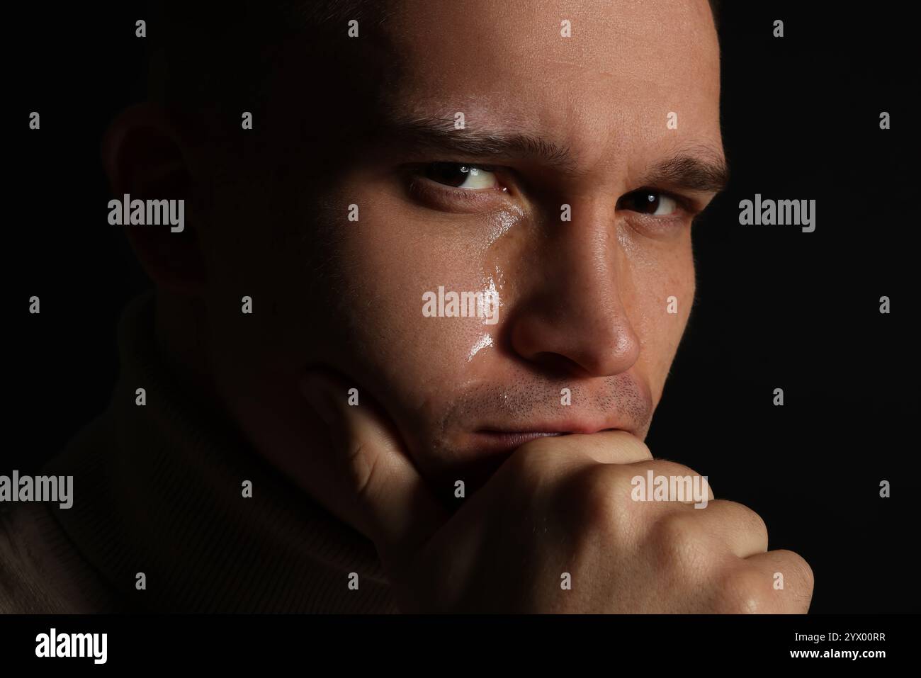 Distressed young man crying on black background, closeup Stock Photo ...