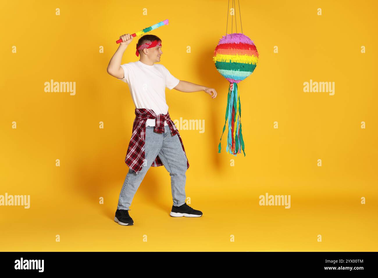 Happy man breaking pinata on yellow background Stock Photo - Alamy