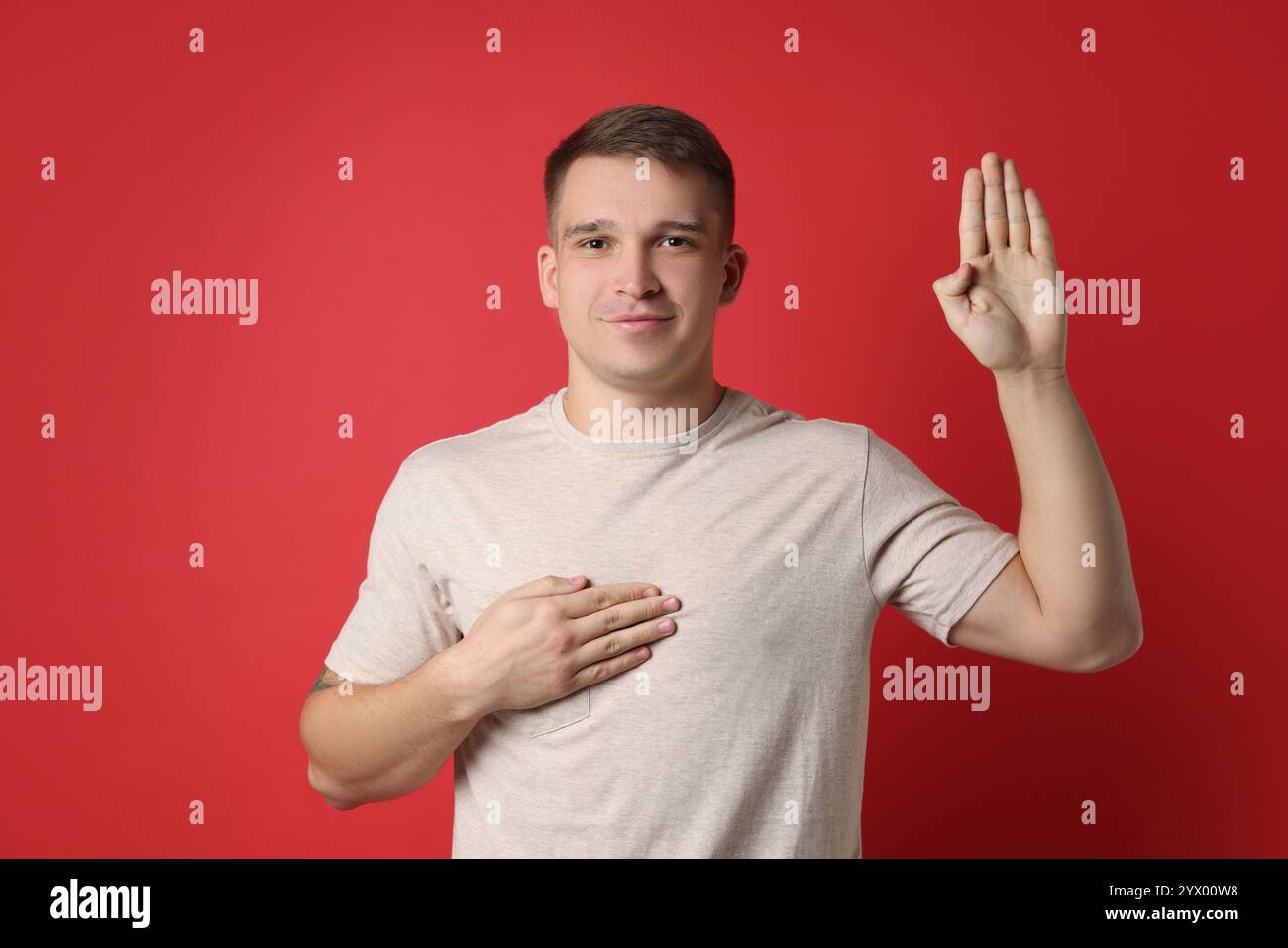Man making promise with raised hand on red background. Oath gesture ...