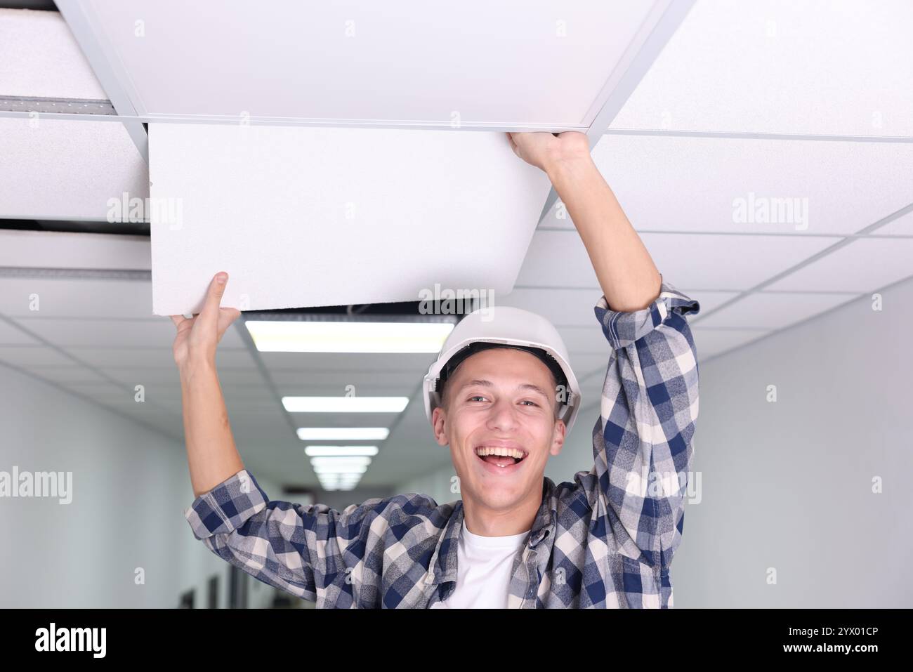 Suspended ceiling installation. Builder working with PVC tile indoors ...