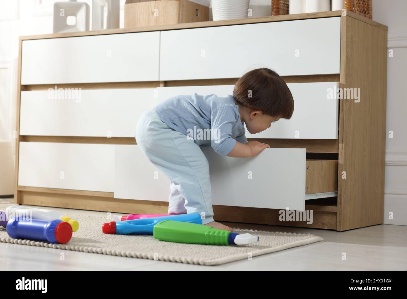 Little boy opening drawer with bottles of detergents at home. Child in ...