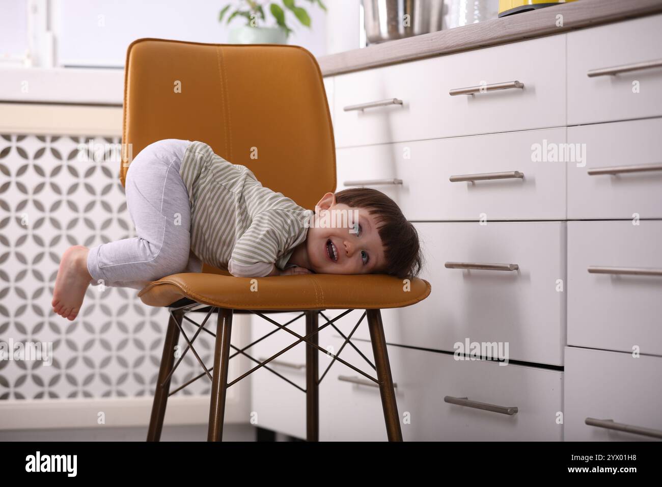 Little boy playing on chair in kitchen. Dangerous situation Stock Photo ...
