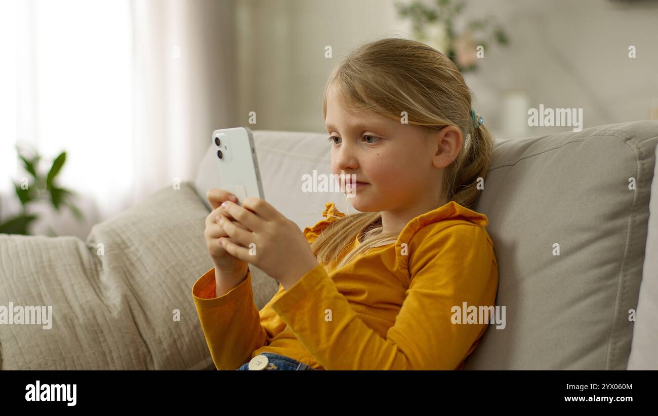 Happy little girl sofa holding mobile phone smartphone rejoice good ...