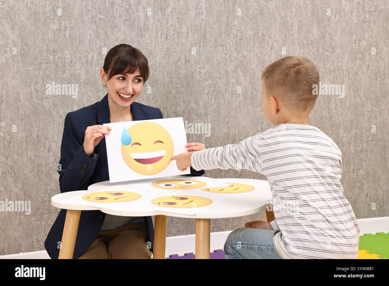 Autism therapy. Little boy choosing emoticon at table with smiling ...