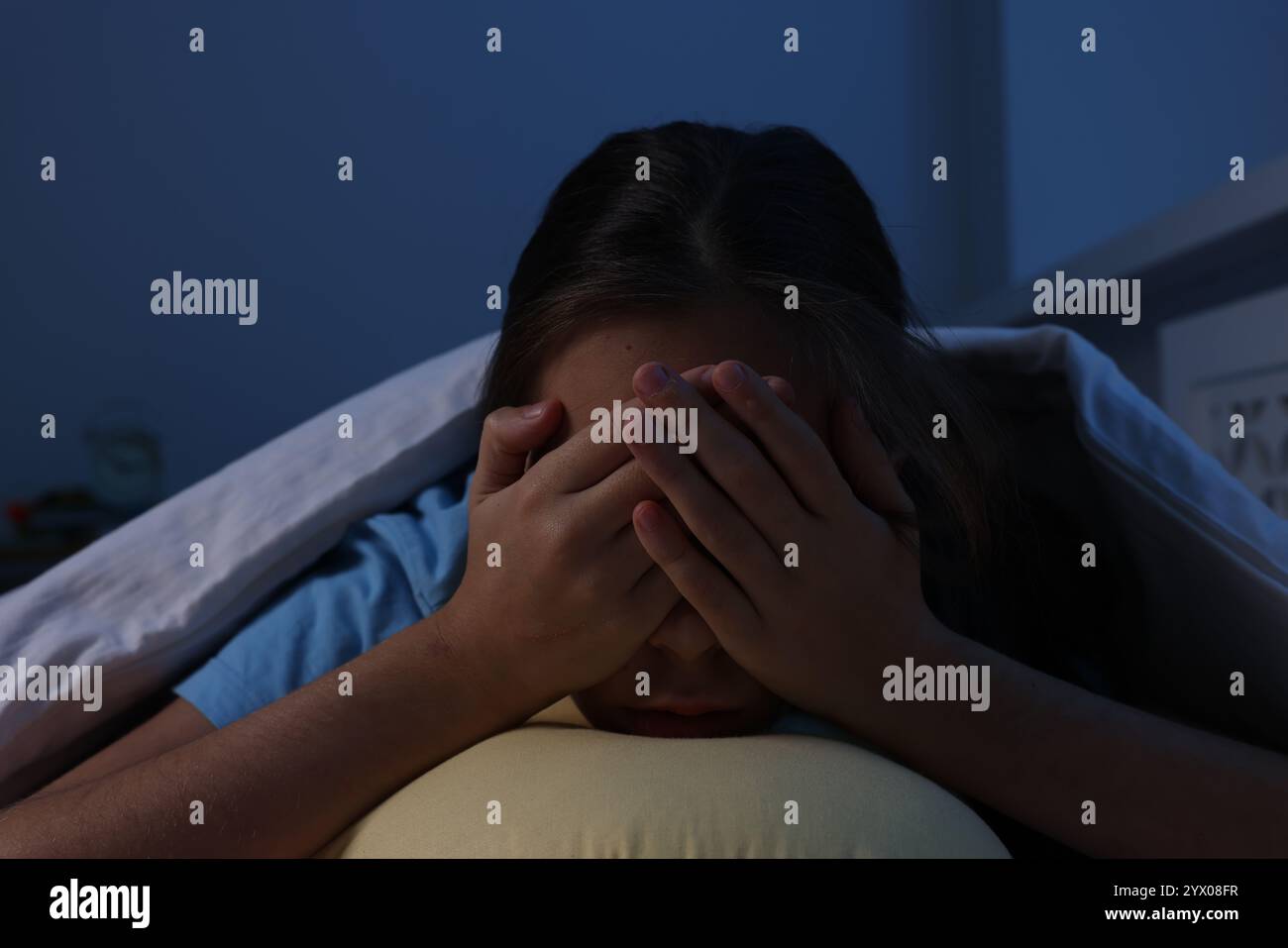 Afraid girl with pillow under duvet on bed at night Stock Photo - Alamy