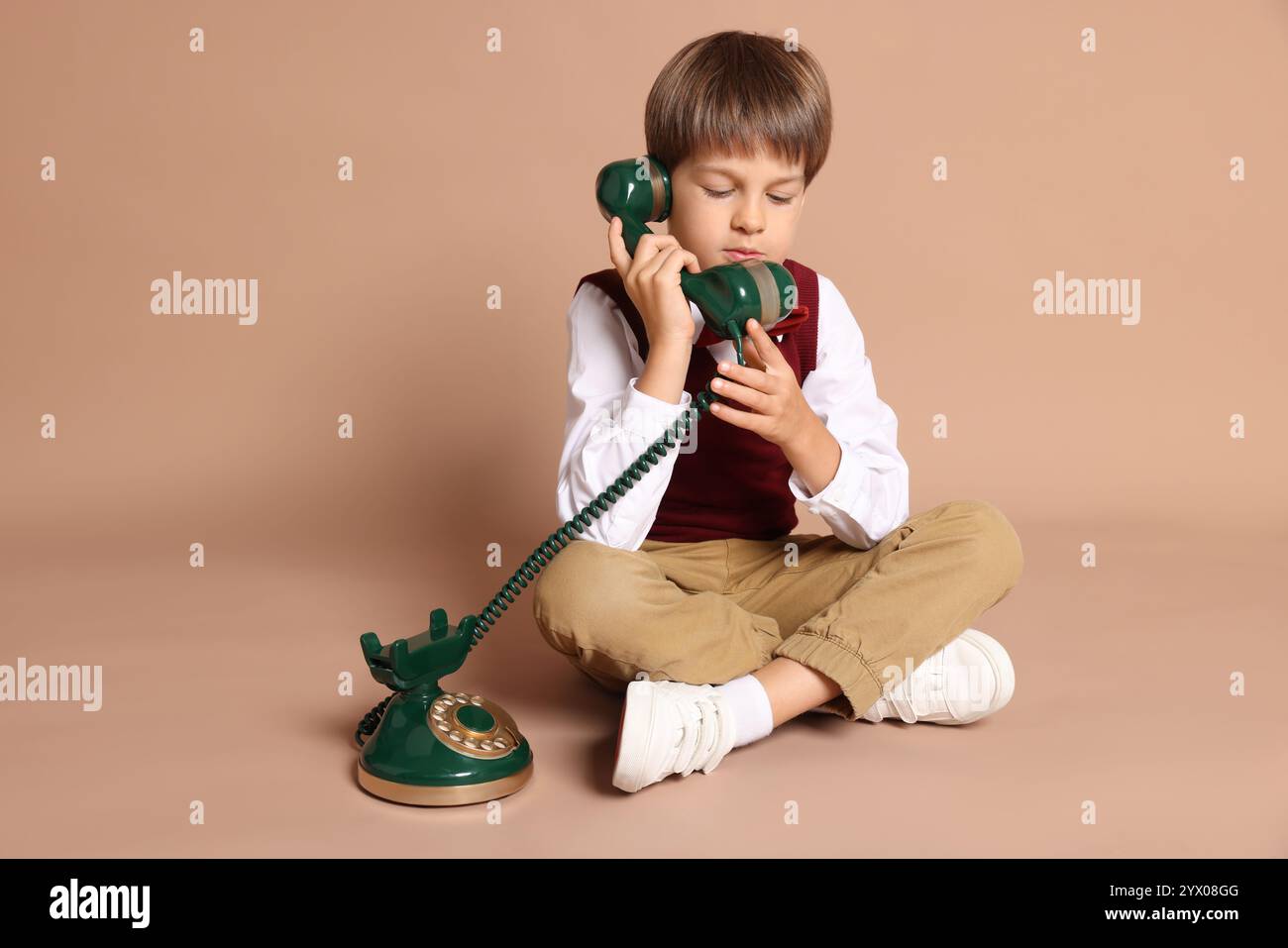 Cute little boy with old telephone on beige background Stock Photo - Alamy