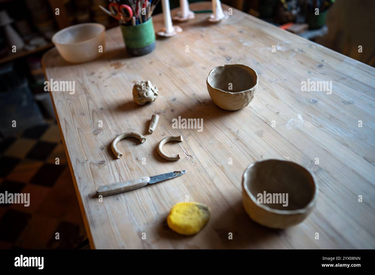 Wooden table with clay blanks, sketches, drying bowls with handles and ...